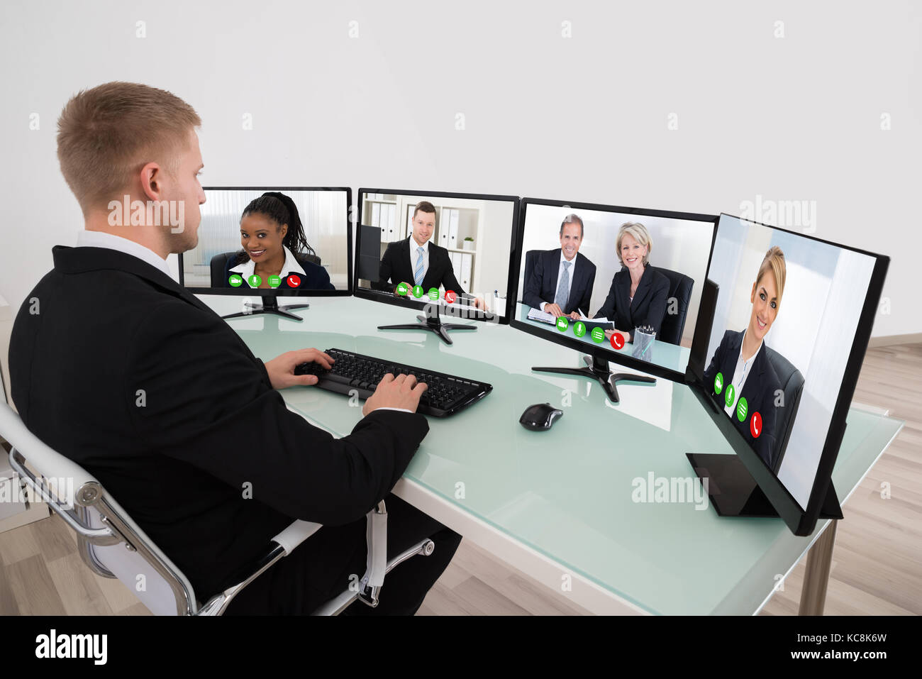 Young Businessman Video Conferencing On Desk With Multiple Computers ...