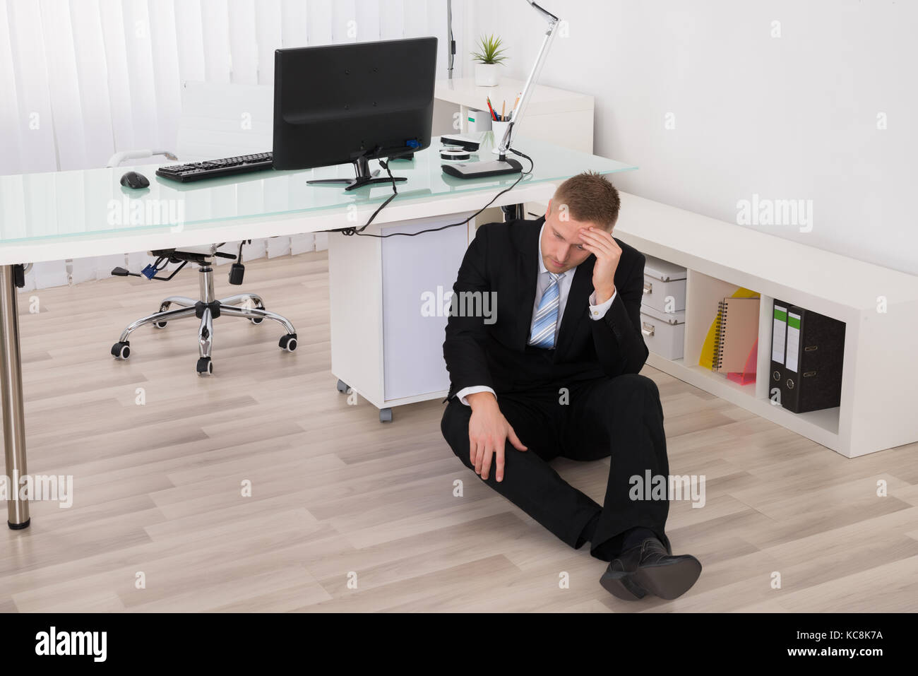 Unhappy Young Businessman Sitting On Floor In Office Stock Photo - Alamy