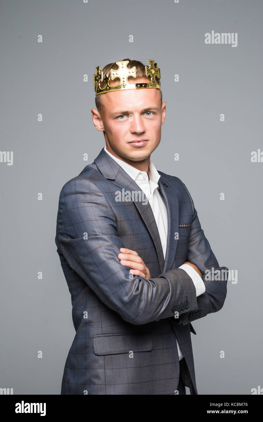 Young attractive man in suit holding above his head a golden crown on a ...