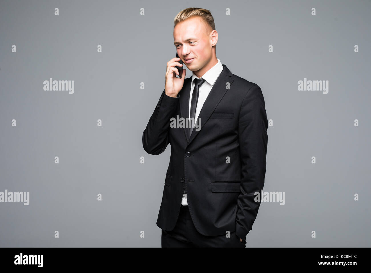 Young attractive man in suit talking on the phone on a gray background ... Young attractive man in suit talking on the phone on a gray background ...