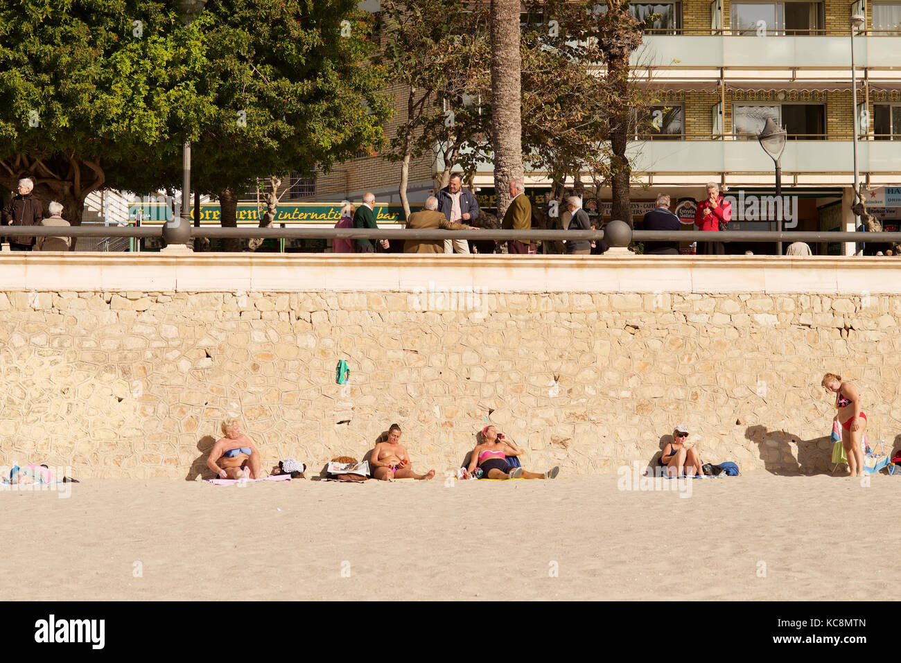 People sunbathing on the beach in contrast to those above Stock Photo ...