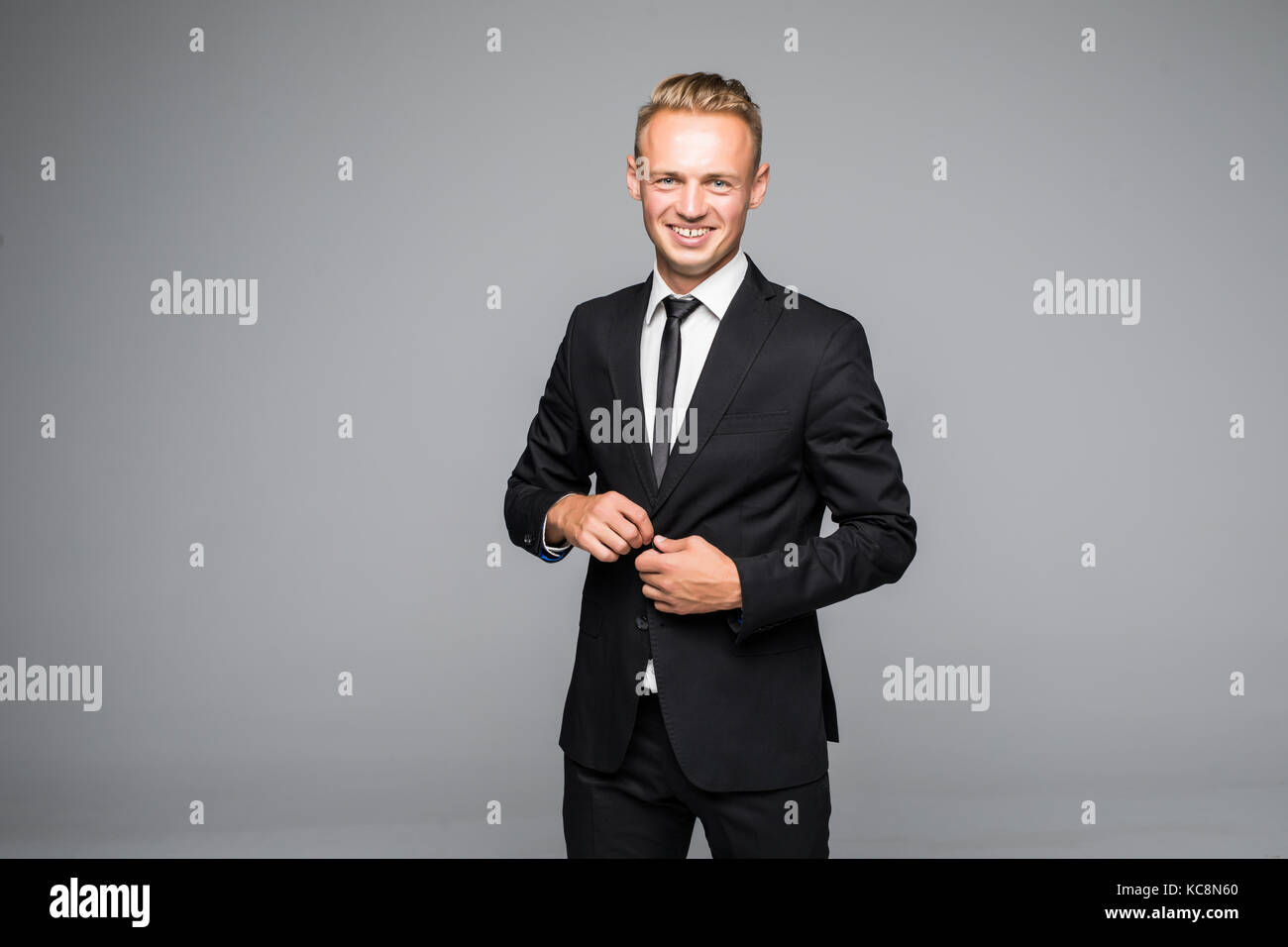 A confident elegant handsome young man standing in front of a grey ...