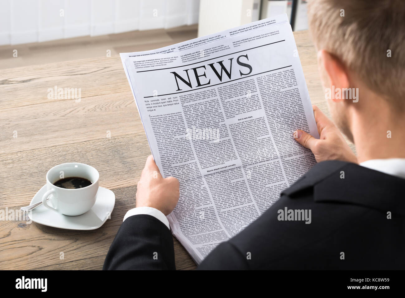 Young Businessman Reading Newspaper At Desk In Office Stock Photo - Alamy