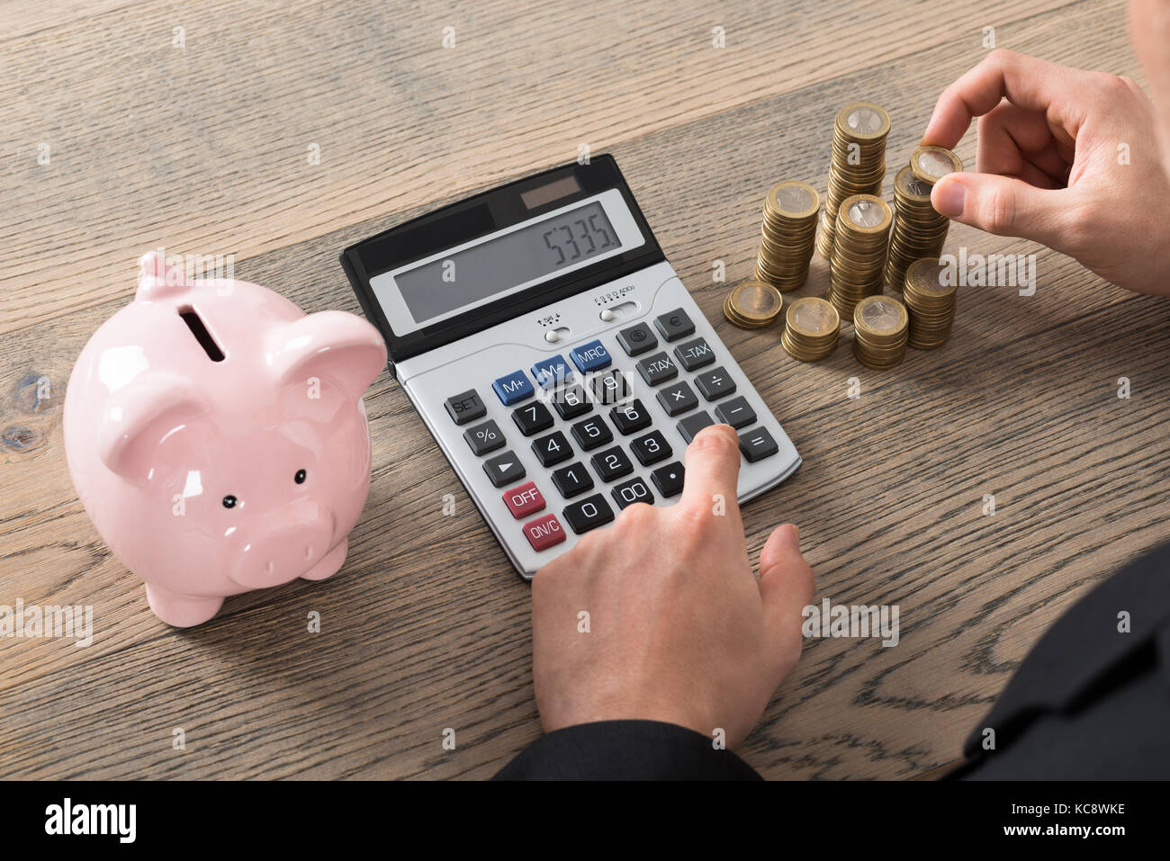 Close-up Of A Businessman Counting Coins Using Calculator At Desk In ...