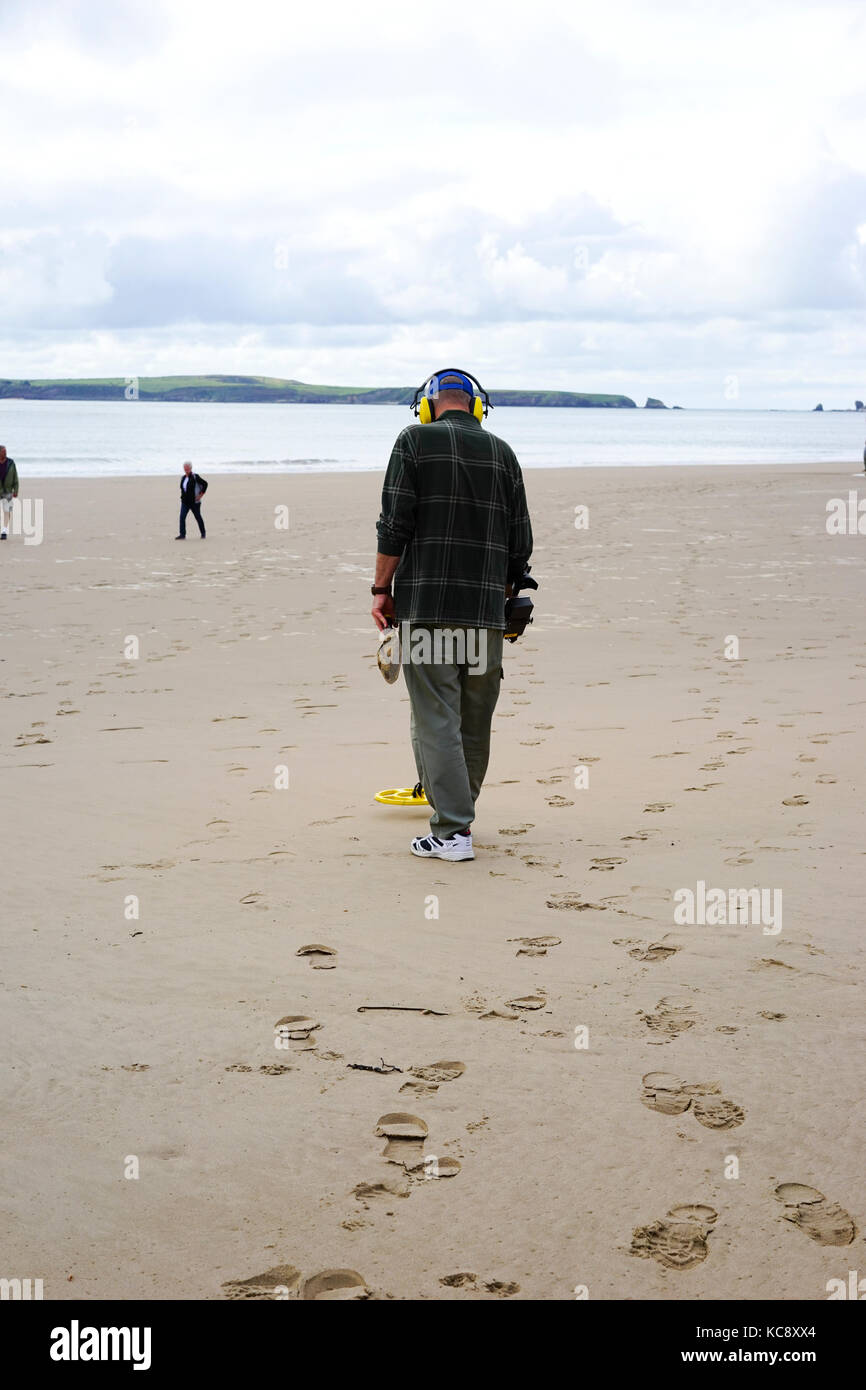 Man using a metal detector on Tenby beach,Penbrokeshire,South Wales, UK ...