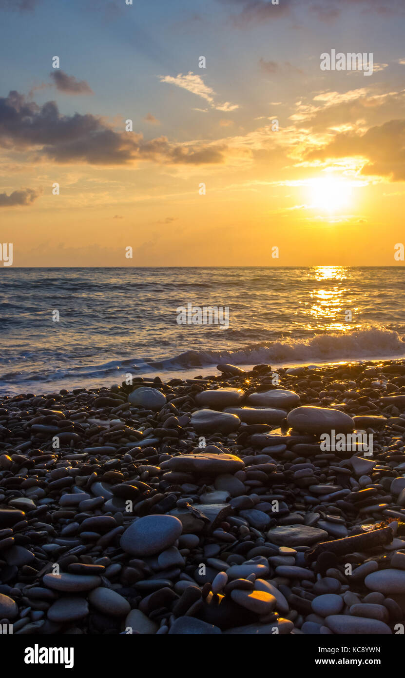 Summer sea sunset on the pebble beach, the sun, waves and clouds ...