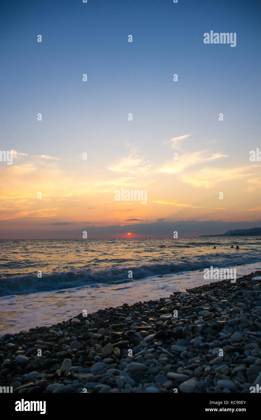 Summer sea sunset on the pebble beach, the sun, waves and clouds ...