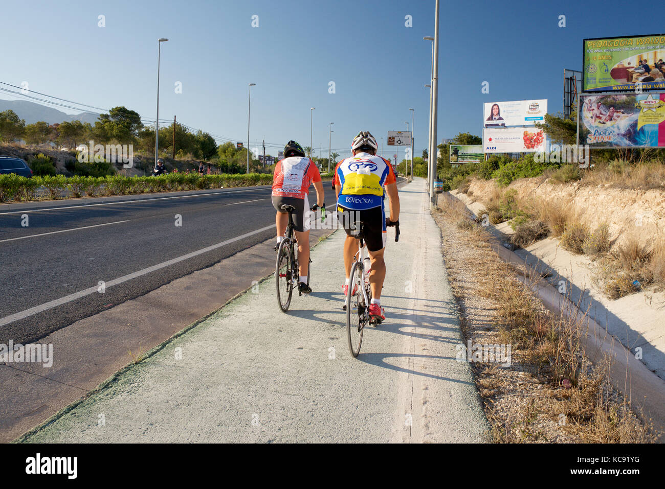 Two cyclists on a path by the roadside cycling Stock Photo - Alamy