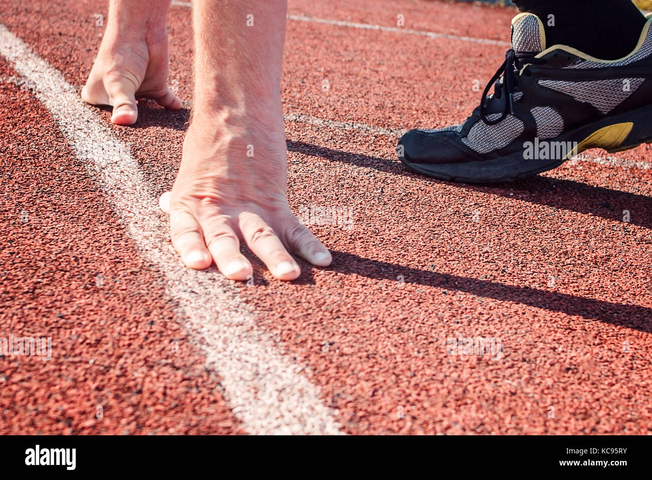 Runner in start position. Hands on starting line. Sport running in ...
