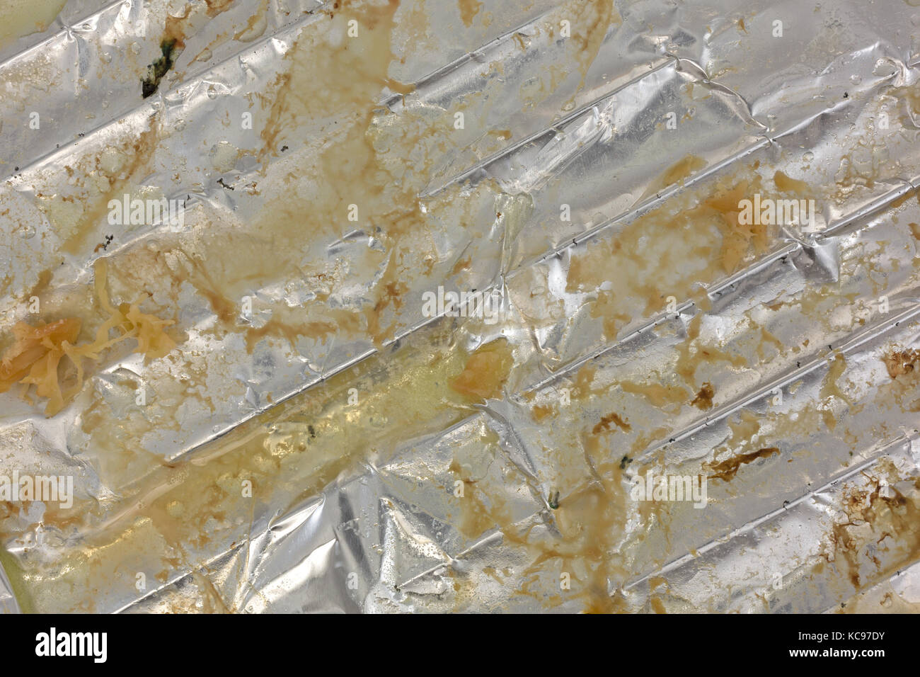 Close view of tinfoil on a wire rack with grease stuck to the surface ...