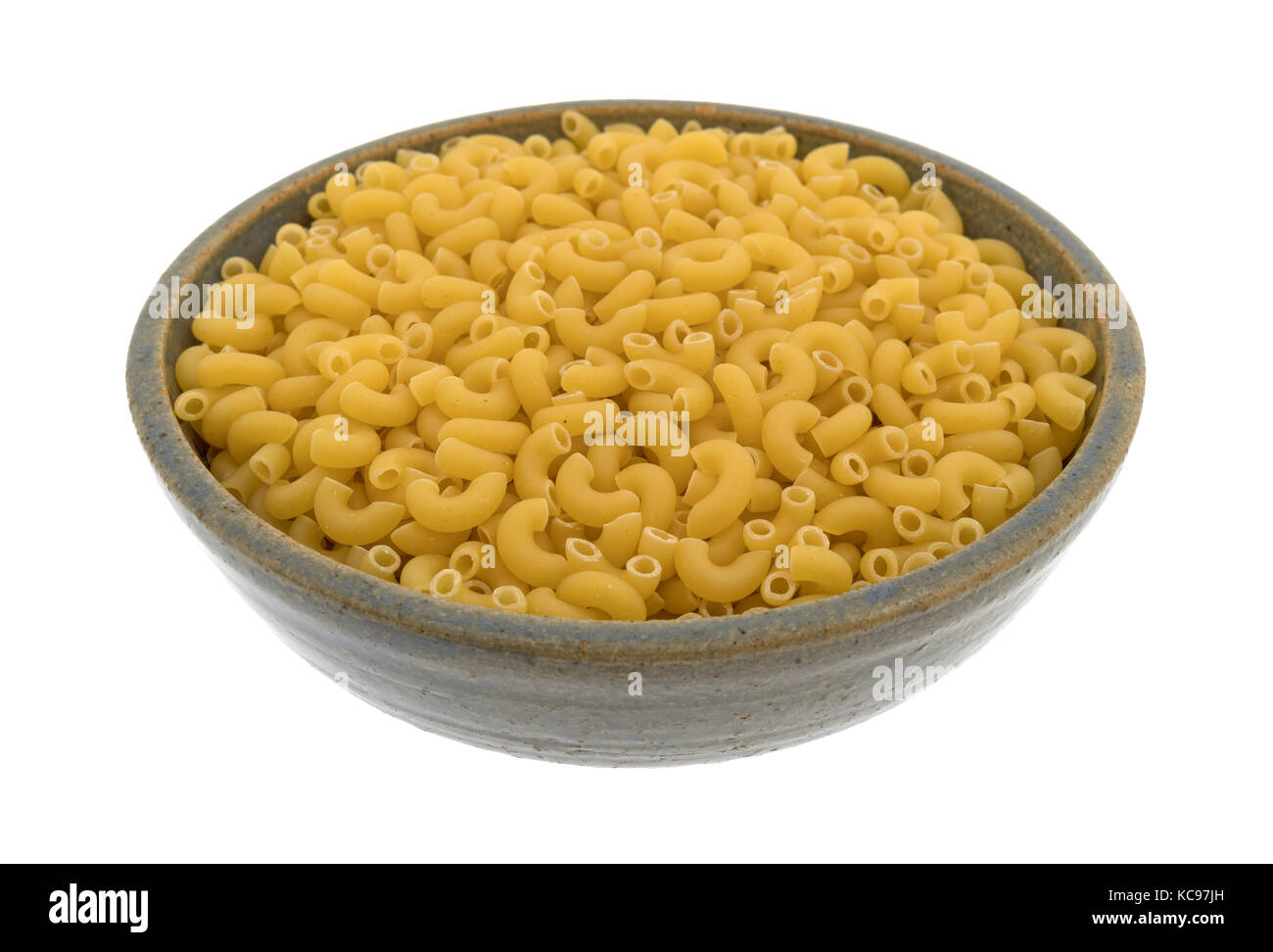 Yellow elbow macaroni in an old stoneware bowl isolated on white ...