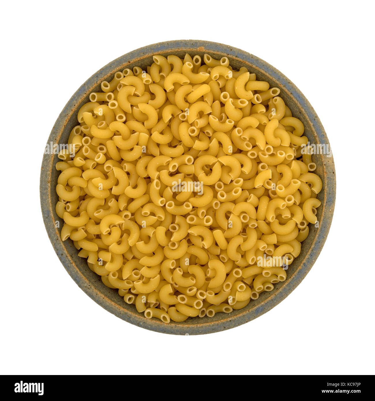 Top view of yellow elbow macaroni in an old stoneware bowl isolated on ...