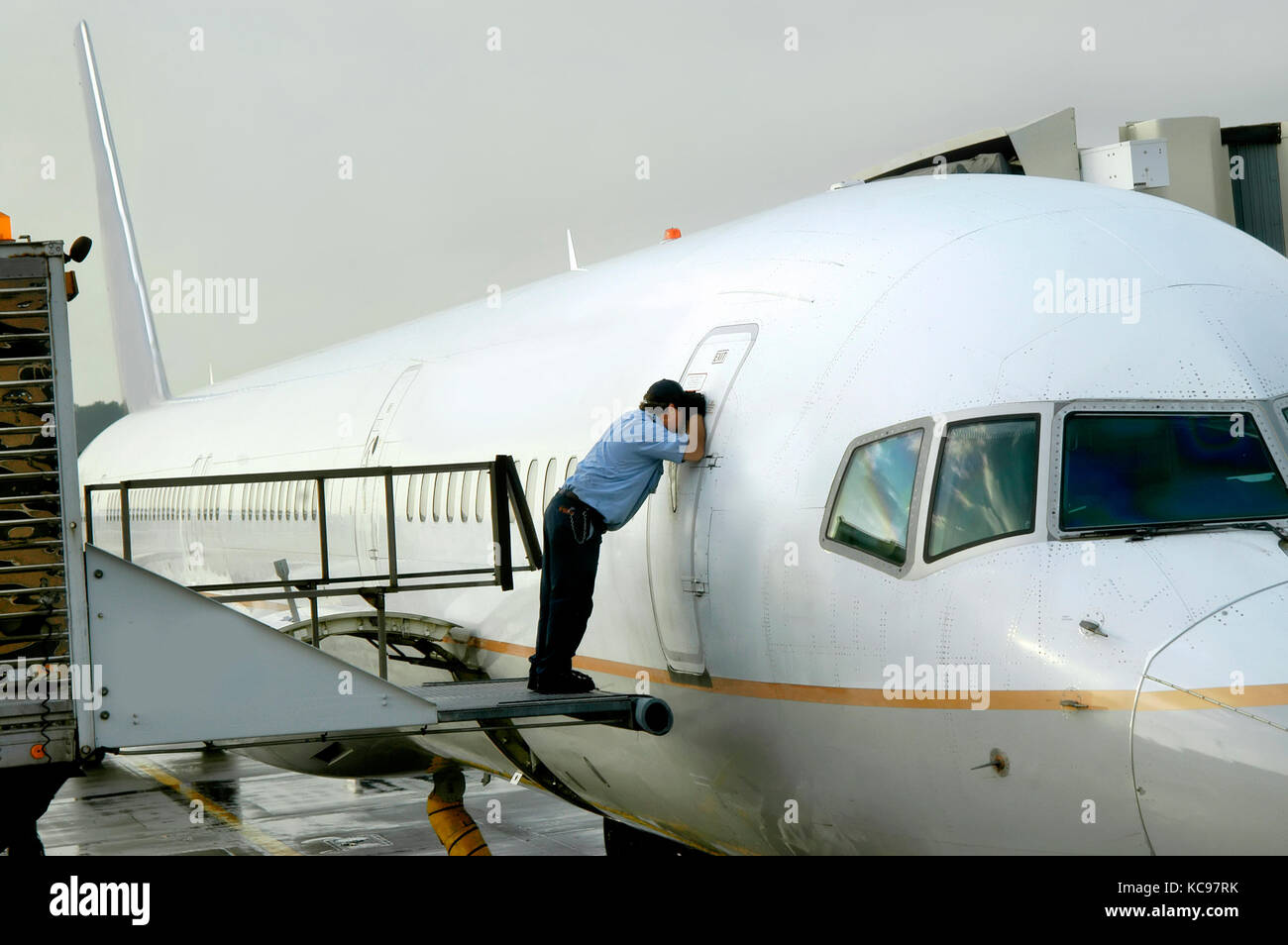 Employee in uniform, peeks through the window of jet. He is standing on ...