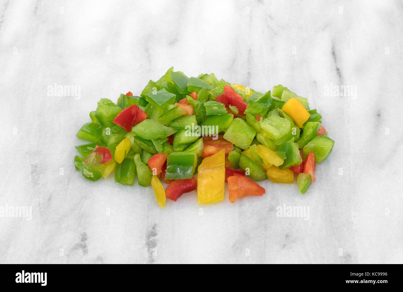 A small pile of chopped red, yellow and green bell peppers on a gray ...