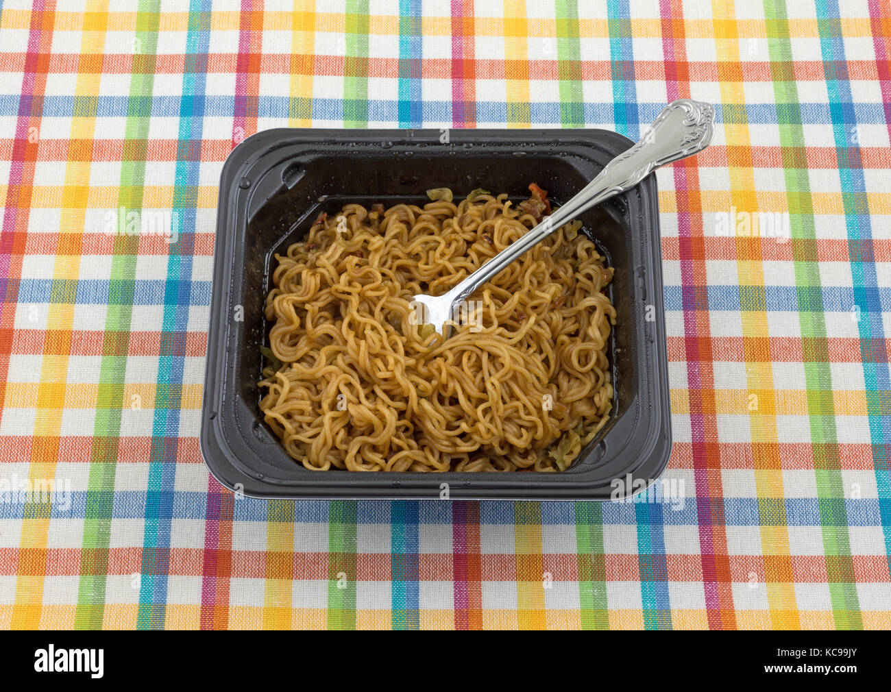 A serving of beef flavored ramen noodles with a fork in a black ...