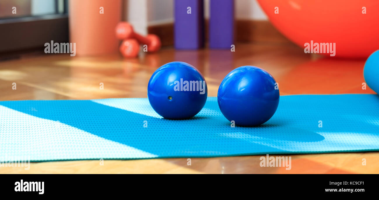 Fitness equipment. Pilates mat and exercise weights on wooden floor ...