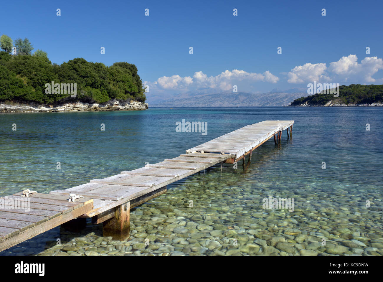 An old wooden jetty on the greek islands with crystal clear waters and ...