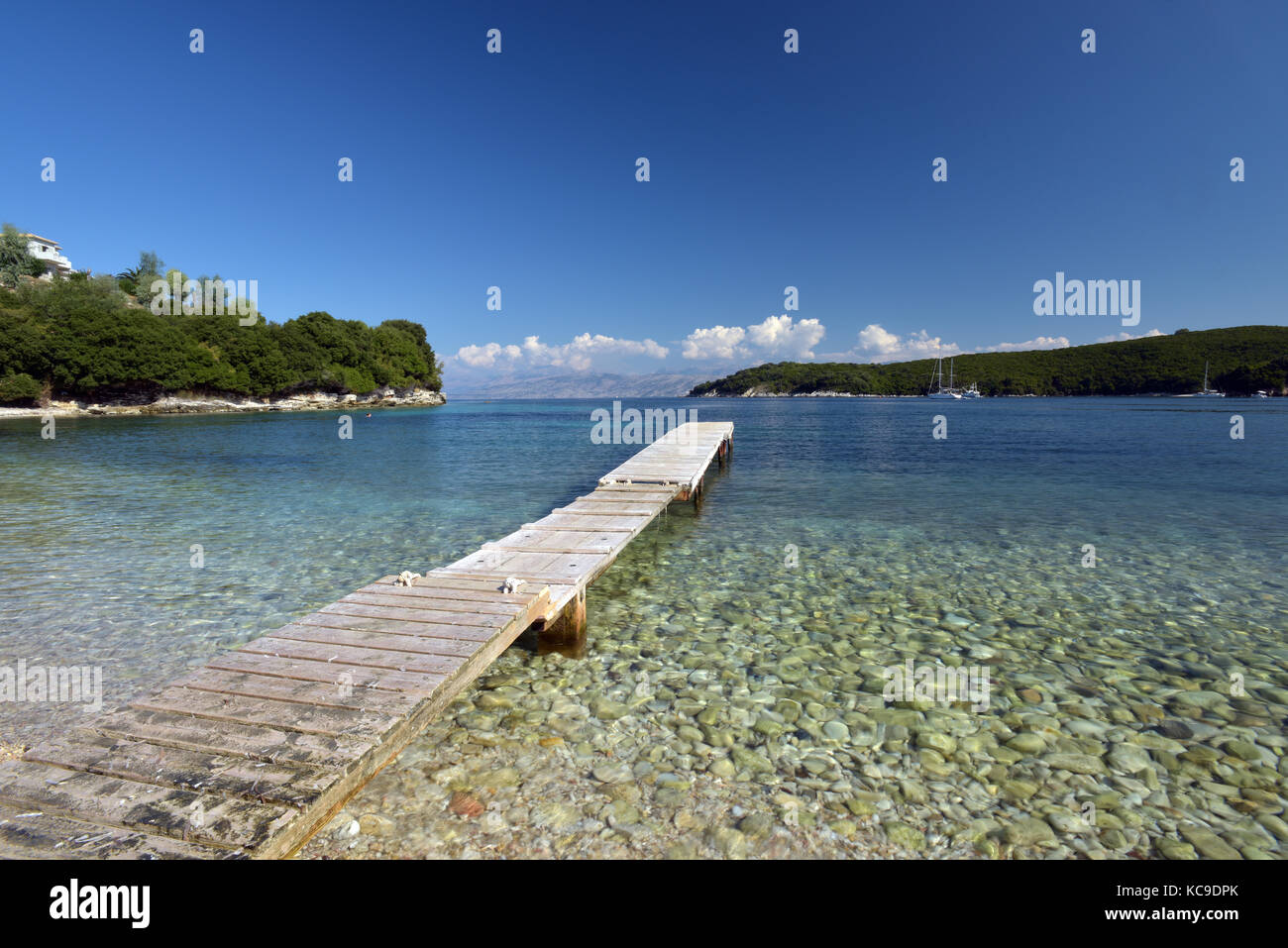 An old wooden jetty on the greek islands with crystal clear waters and ...