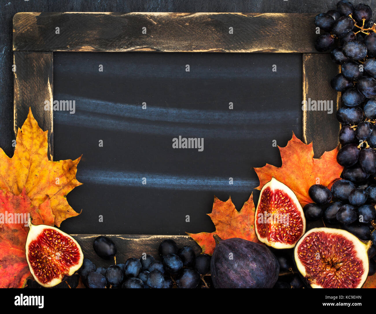 Autumn frame with chalk board, leaves, figs and grape, top view, space ...