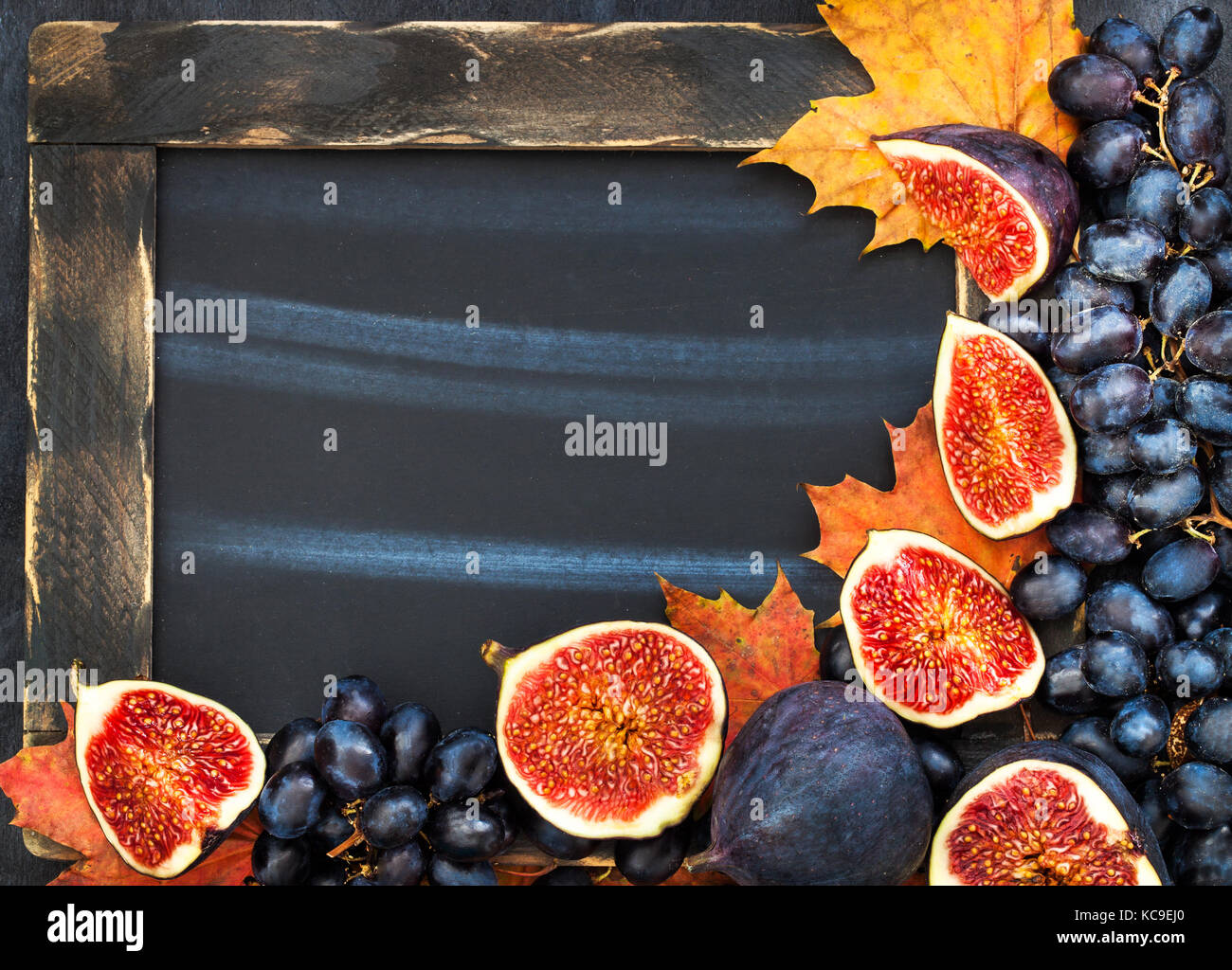 Autumn frame with chalk board, leaves, figs and grape, top view, space ...