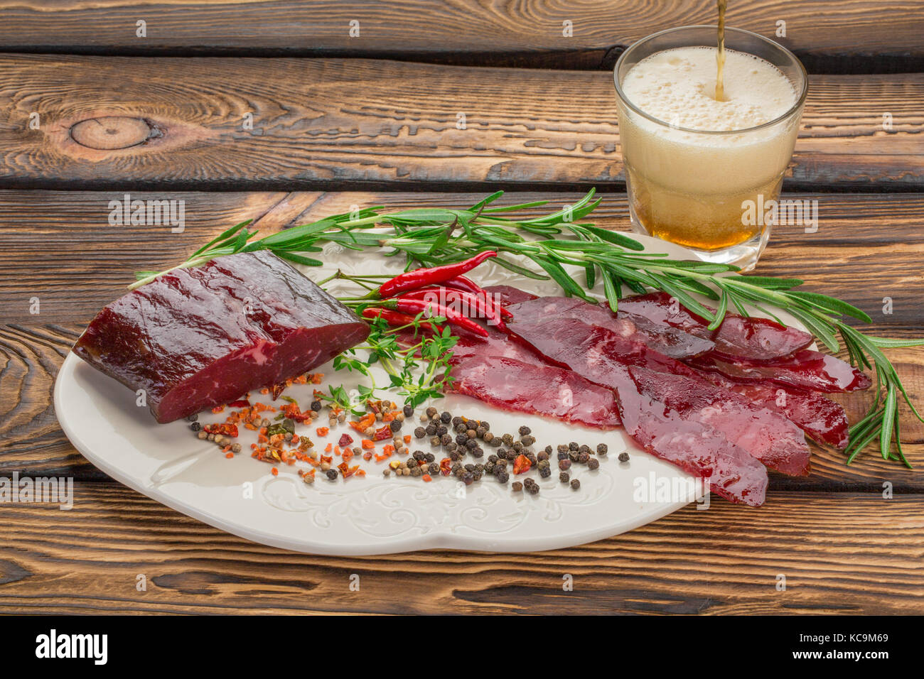 Dry meat with fresh herbs, chilli, condiments on a plate. beer is ...