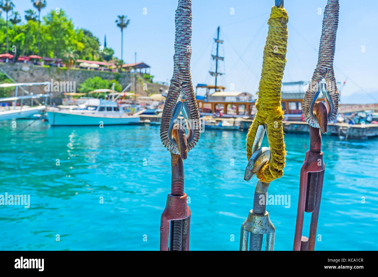 The close-up of the hooks and ropes of a ship mast with boats and ...