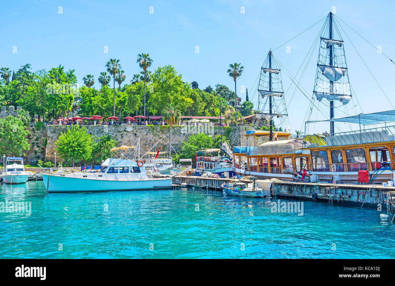 The old and modern ships in Antalya marina with a fortress wall and ...