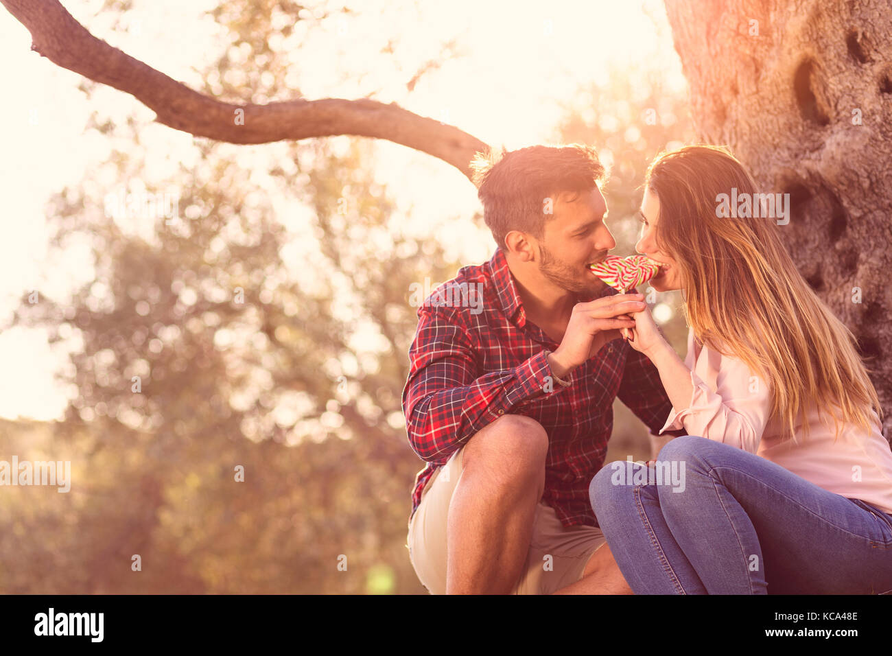 Young beautiful couple under tree in beautiful nature Stock Photo - Alamy