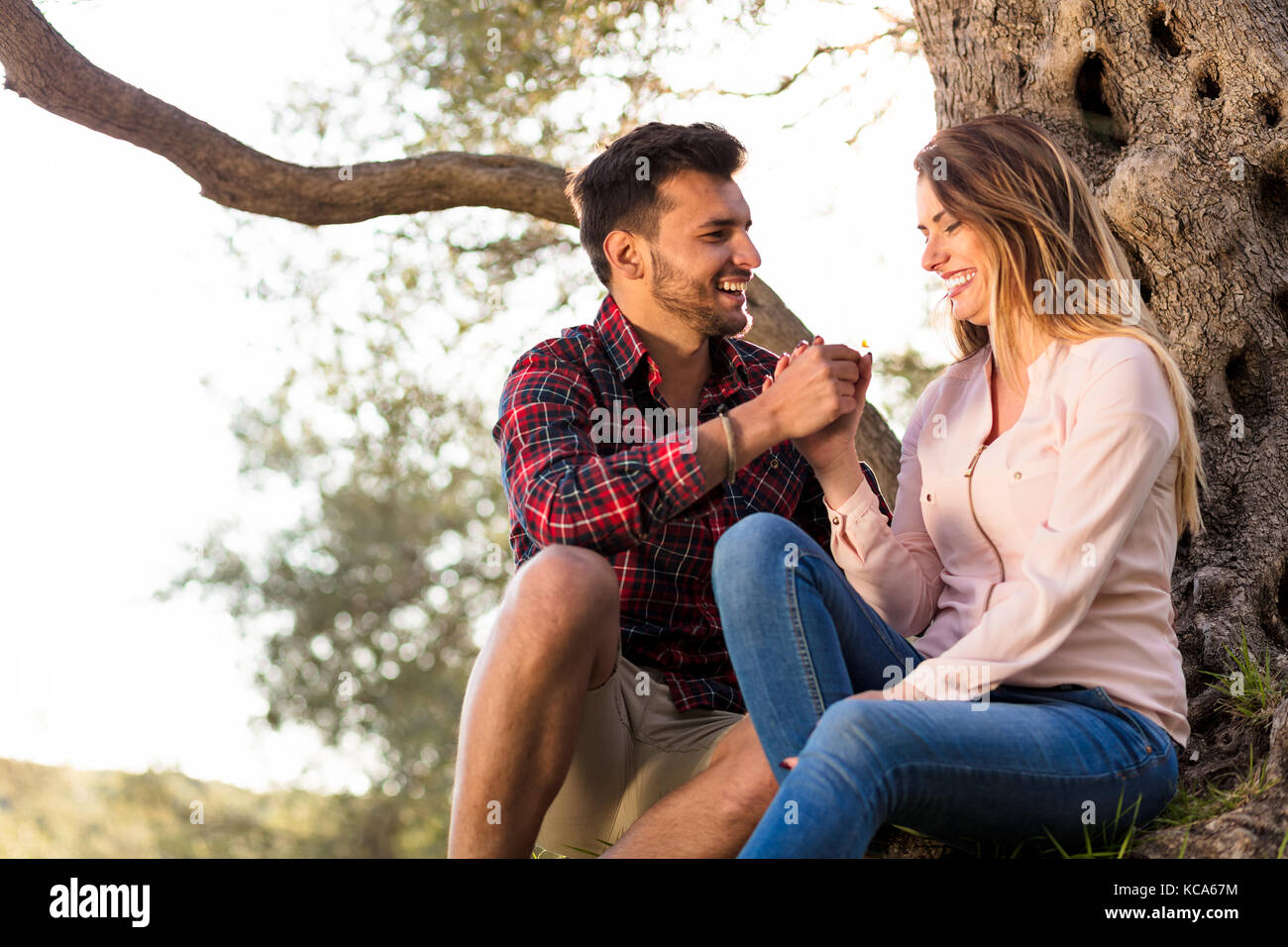 Young beautiful couple under tree in beautiful nature Stock Photo - Alamy