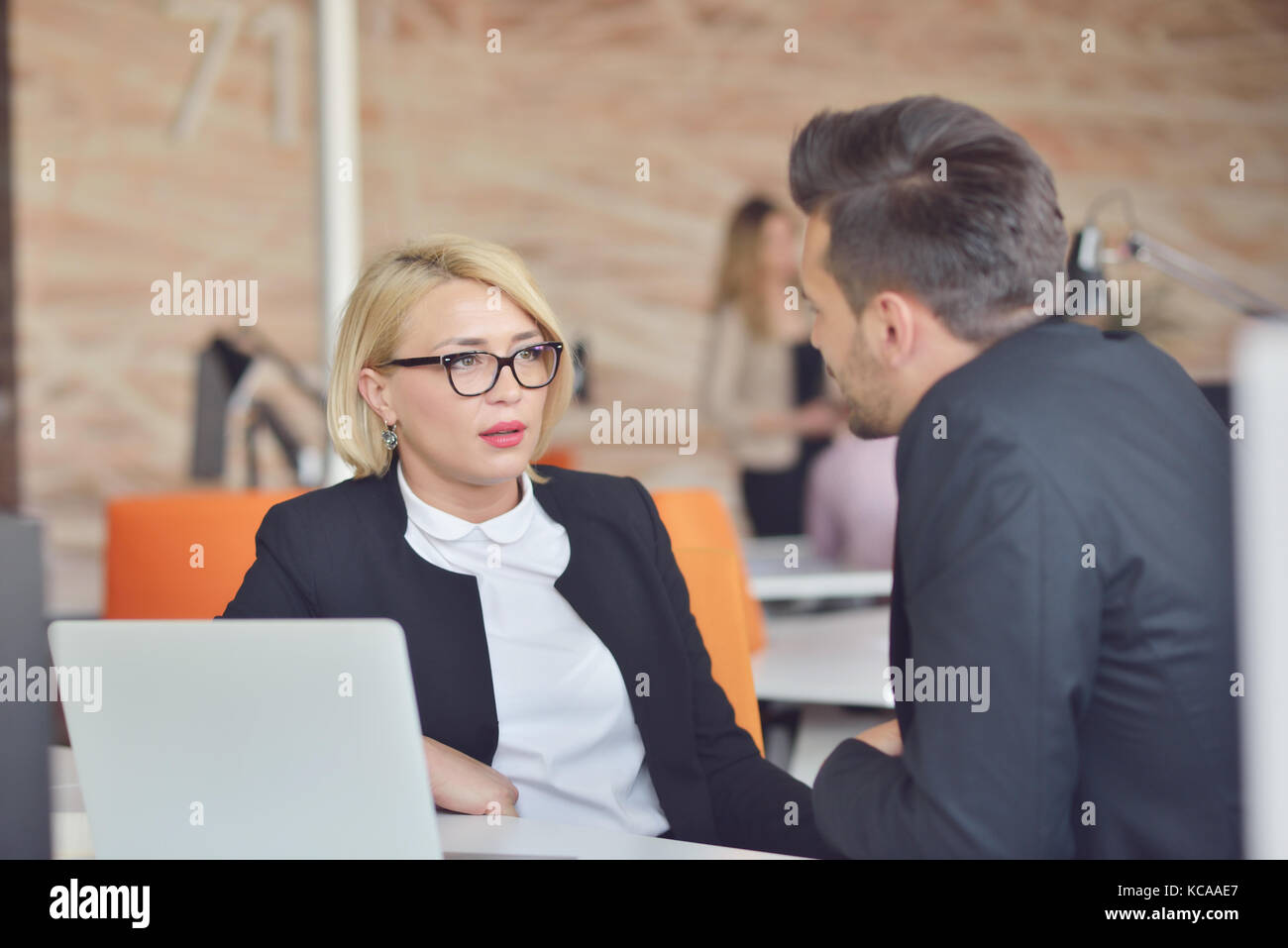 Beautiful young business partners are using a laptop, discussing ...