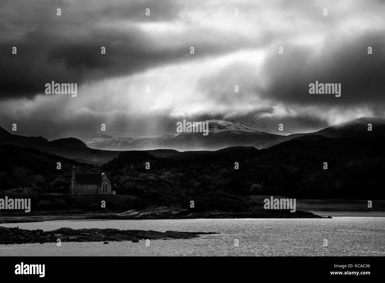 Dramatic rain clouds over a church on the shore of Loch Gairloch in the ...