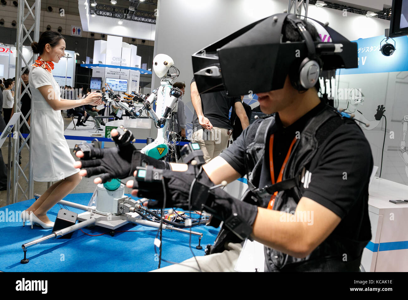 A booth assistant interacts with a master-slave robot TELESAR V while a ...