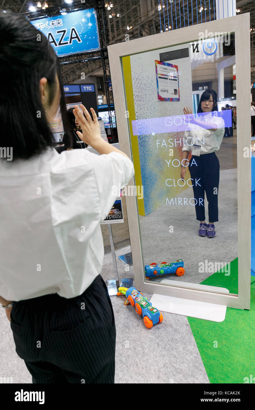 An exhibitor gives a demonstration of a magic mirror at CEATEC Japan ...