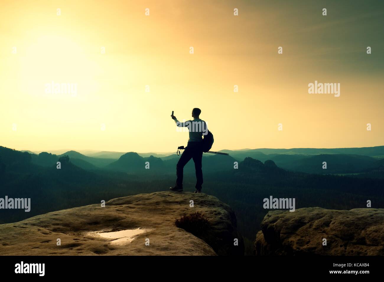 Strong man hiker taking photo with smart phone at mountain peak ...