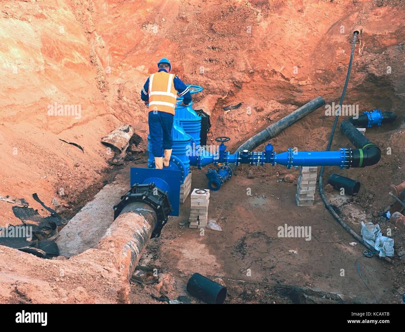 Worker in safety clothes drive valve conduit on City potable water pipe ...