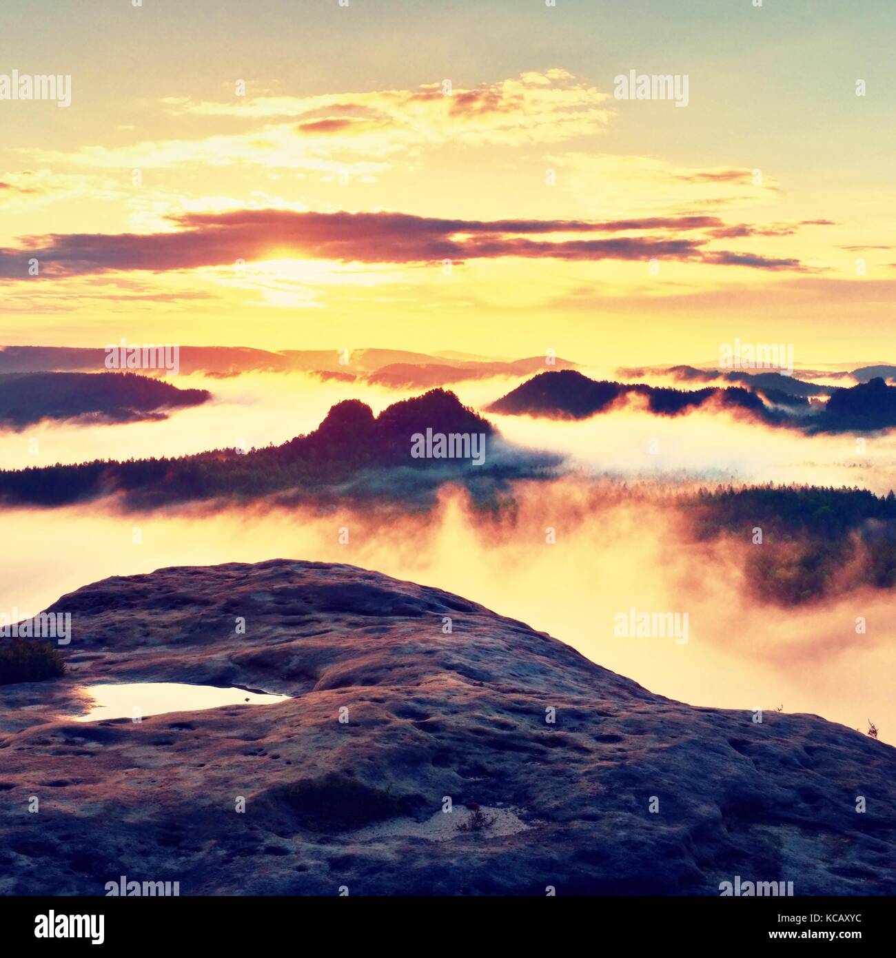 View over wet sandstone rocky peak into forest valley, daybreak Sun at ...