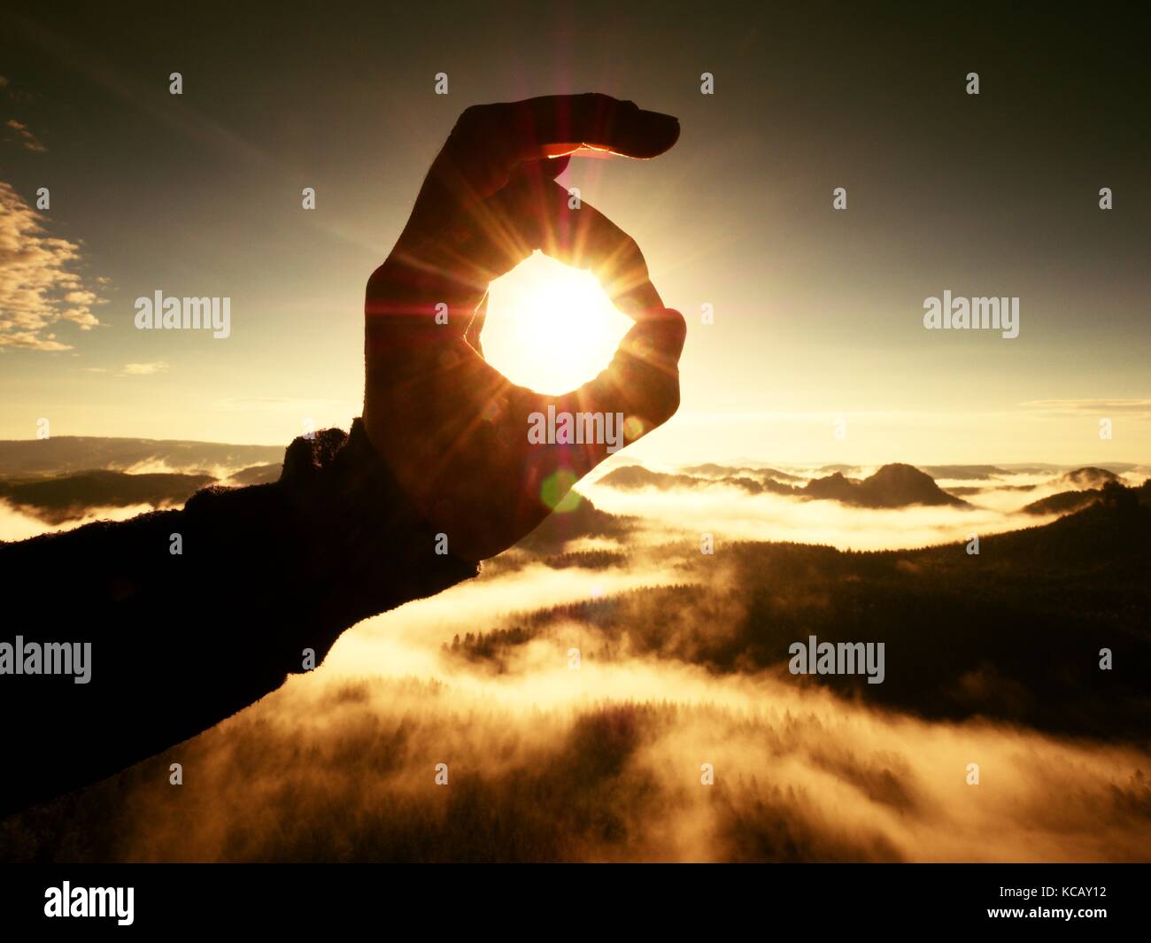 Man hand touch Sun. Misty daybreak in a beautiful hills. Peaks of hills ...