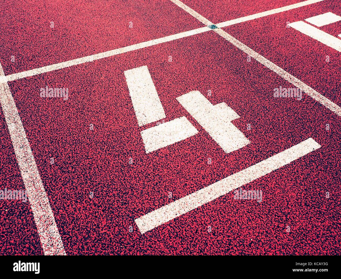 Number four. White track number on red rubber racetrack, texture of ...