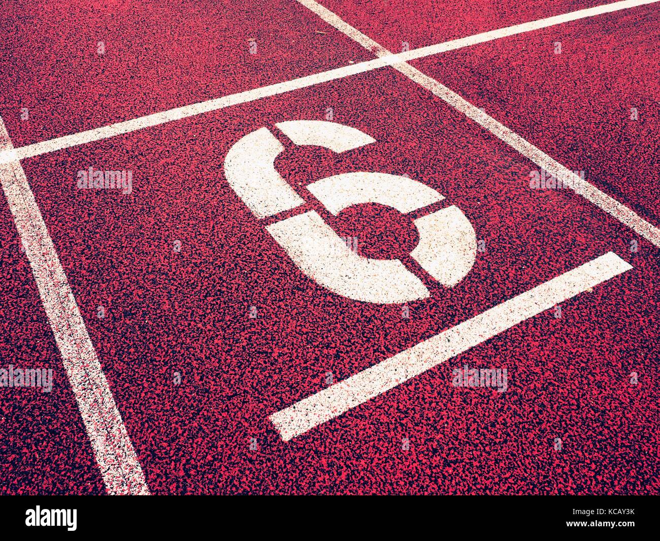 Number six. White athletic track number on red rubber racetrack ...