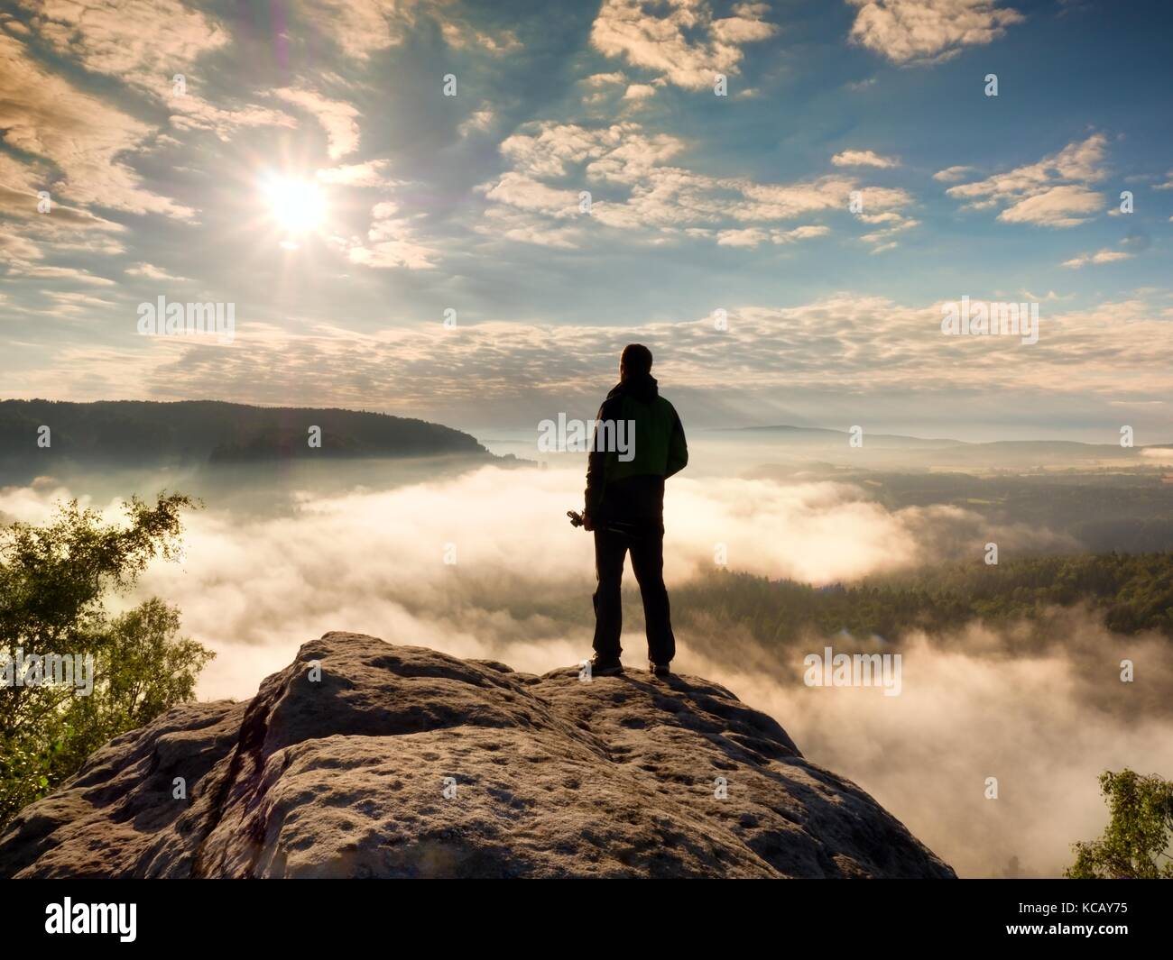 Professional photographer with tripod in hands on cliff and thinking ...