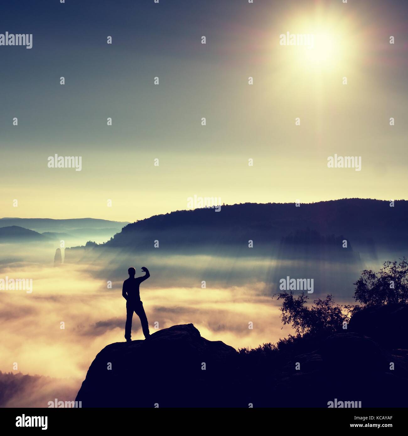 Man shadowing eyes. Alone tourist on cliff edge and watching into deep ...