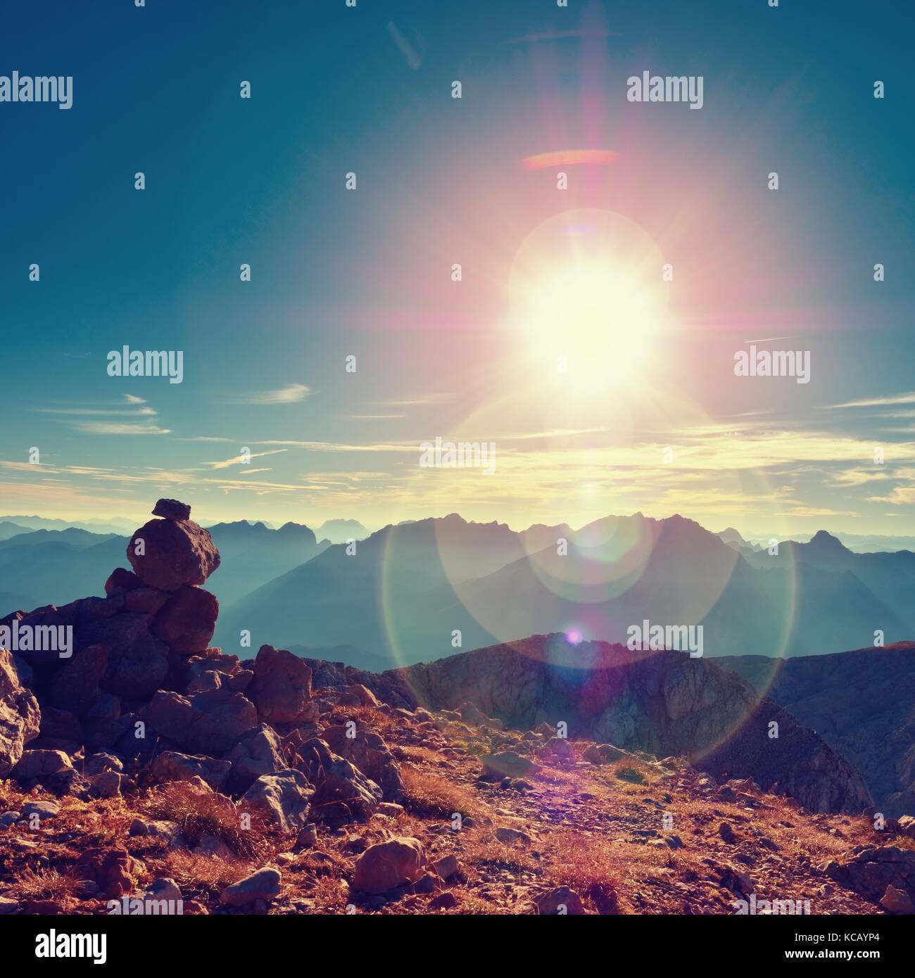 Lens flare light, strong defect. Balanced stone pyramide on stony peak ...