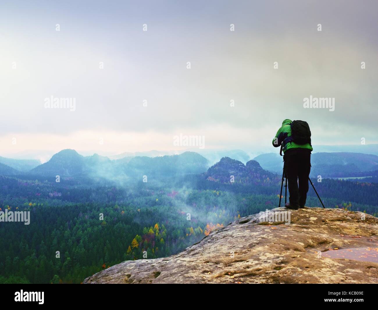 Professional photographer in green jacket with backpack takes photos ...