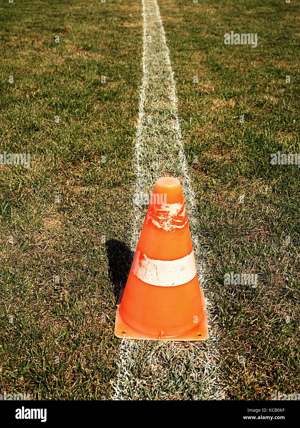 Bright orange white plastic cone on painted white line. Very dry ...