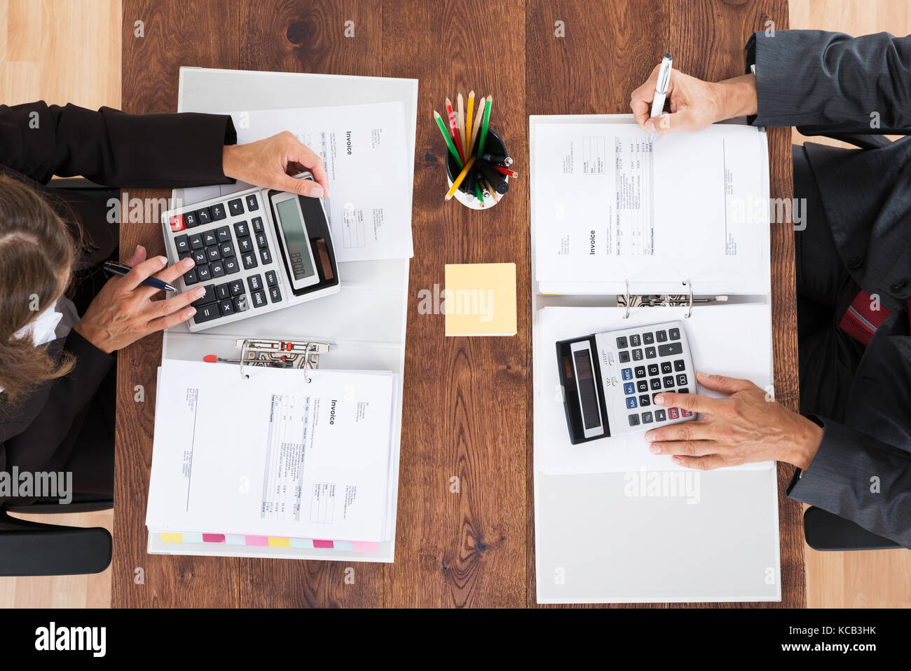 Two Accountants Calculating Tax Invoice Using Calculator On Wooden Desk ...