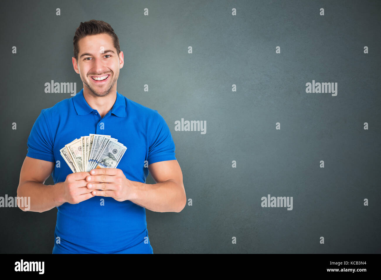 Young Happy Man Holding Fanned Currency Note On Gray Background Stock ...