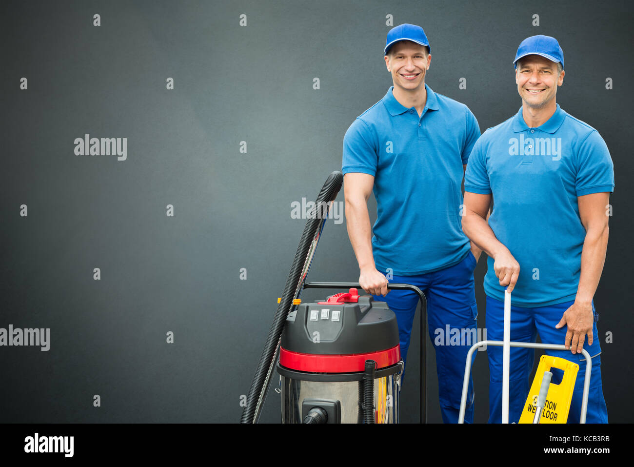Portrait Of A Two Happy Male Cleaners With Cleaning Equipment Standing ...