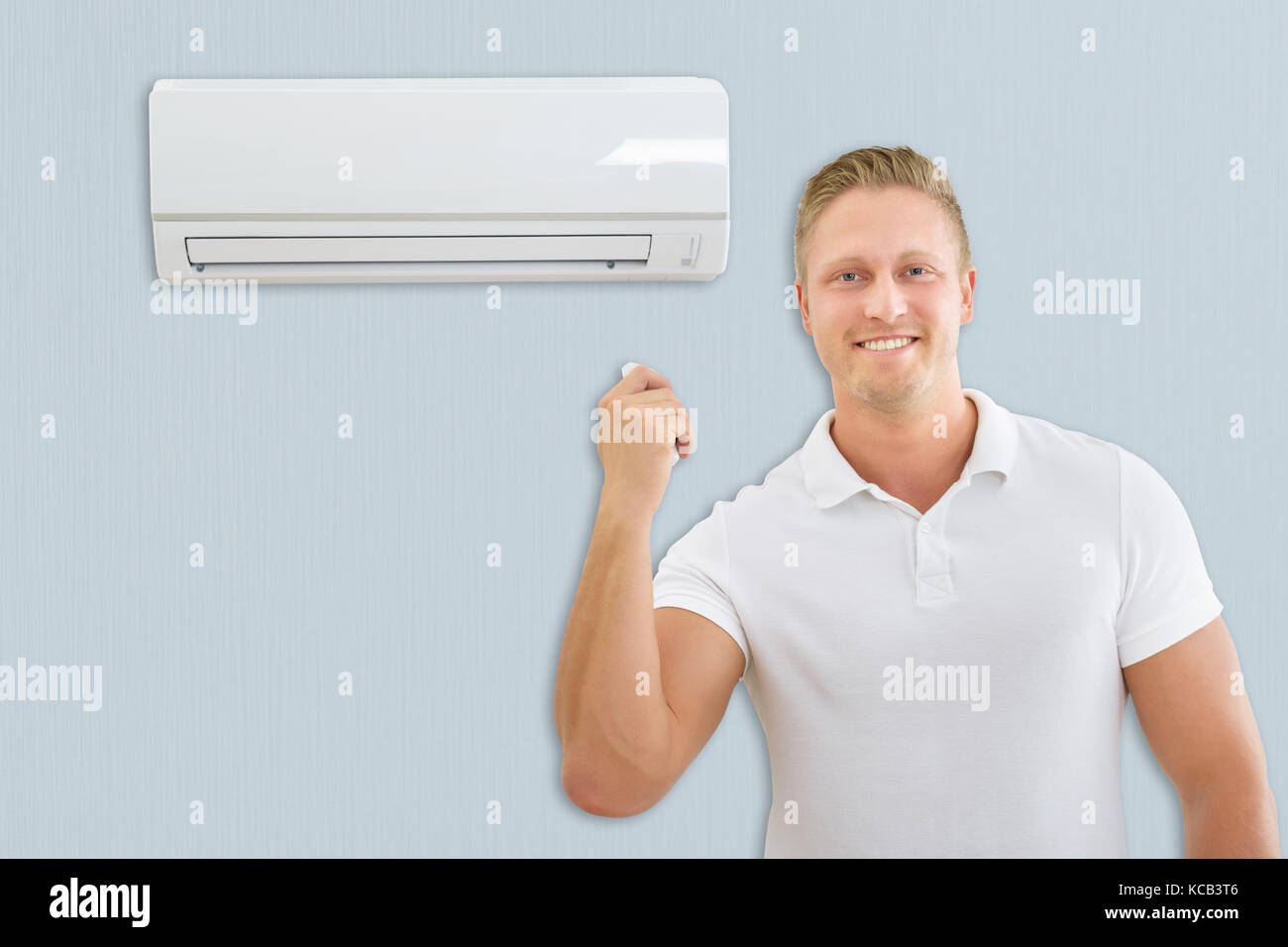 Portrait Of A Young Man Using Air Conditioner At Home Stock Photo - Alamy