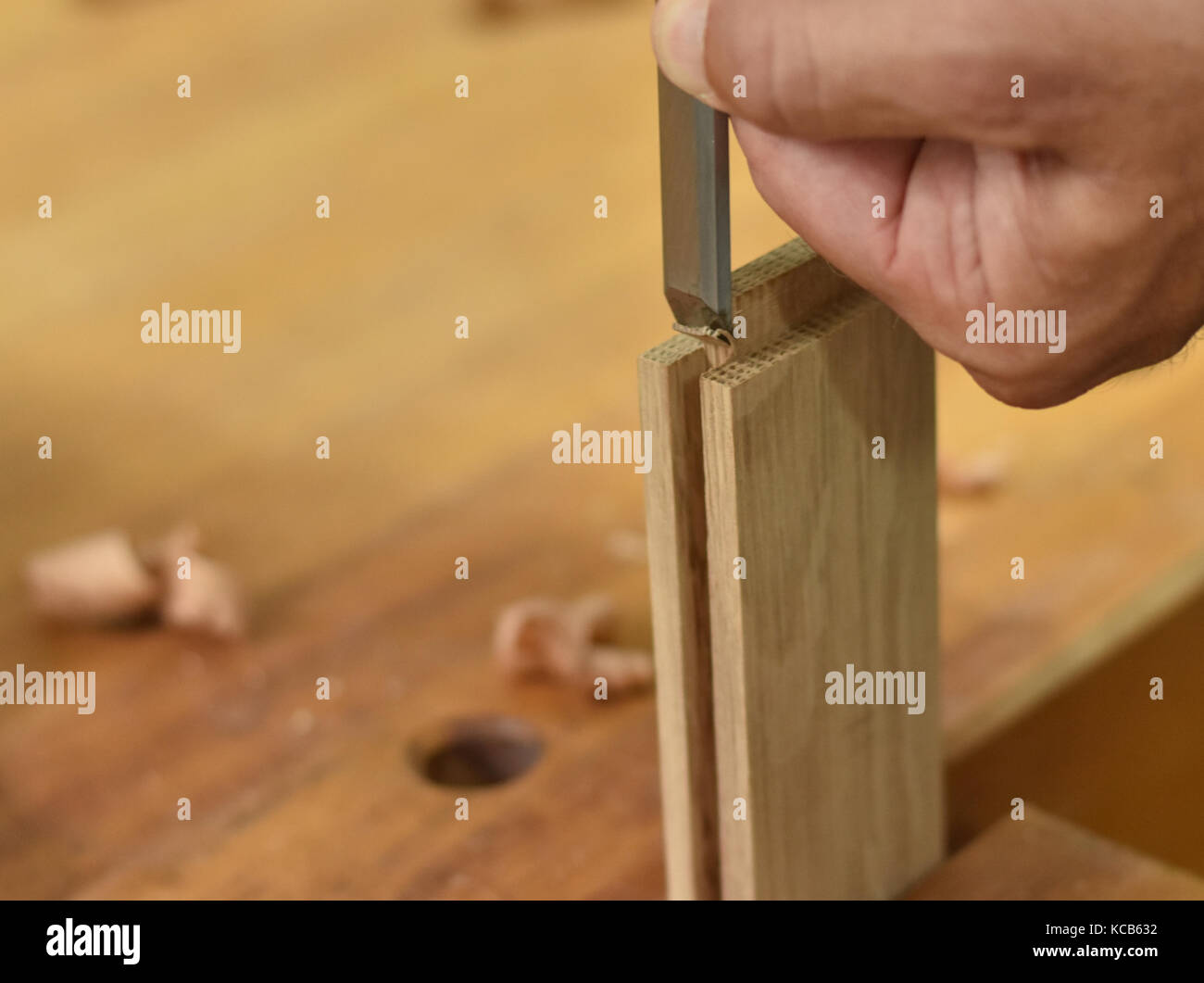 Using a paring chisel to remove wood shavings from a mortise and tenon ...