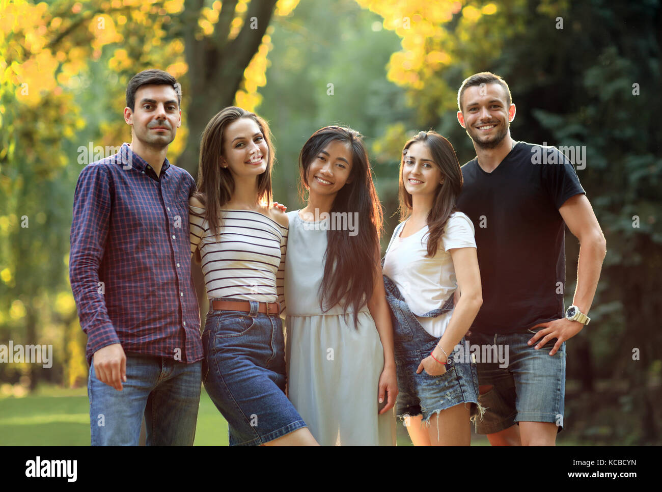 Five young people friends looking at camera in sunny park. Beautiful ...